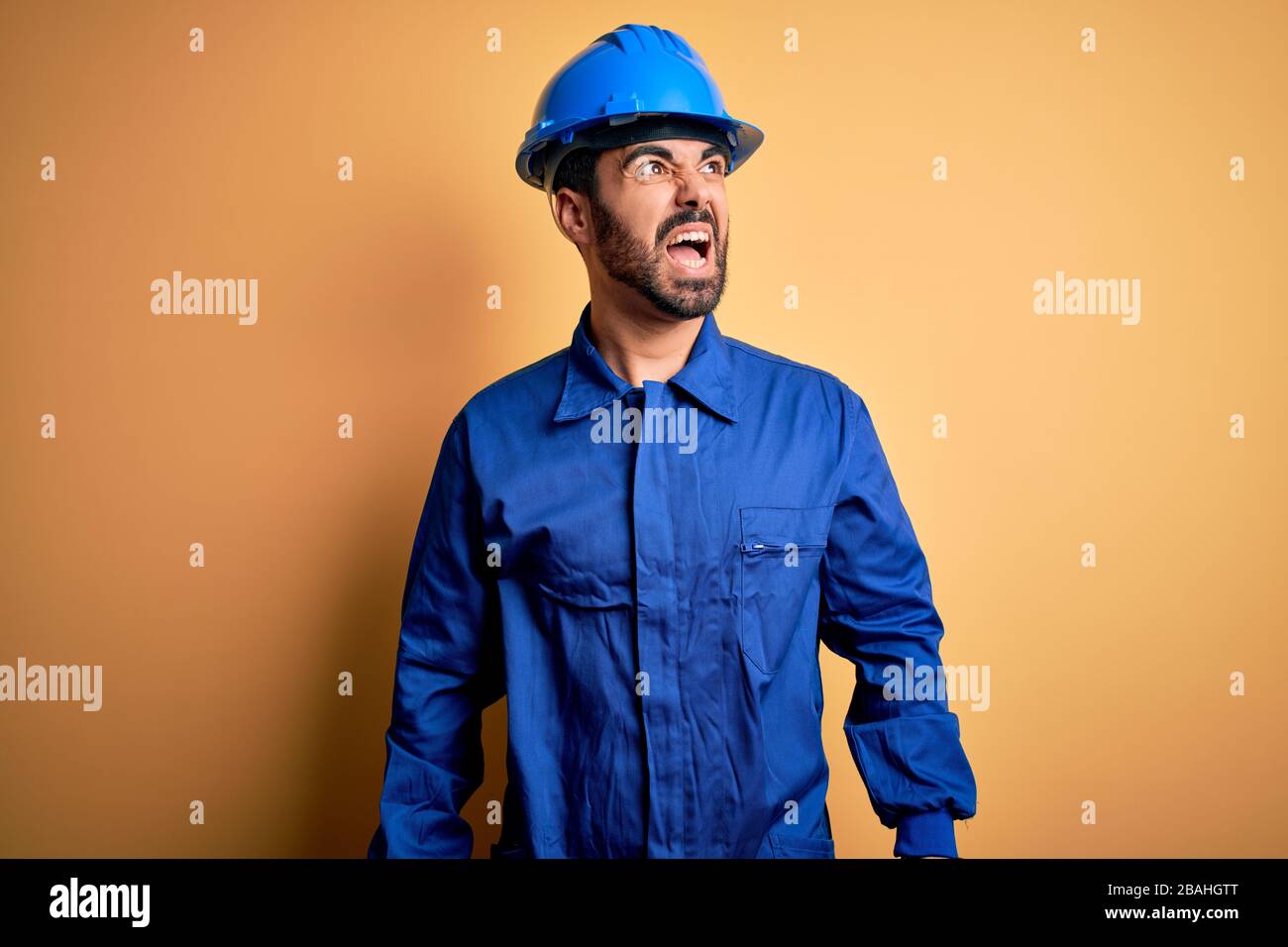 Mechanic man with beard wearing blue uniform and safety helmet over ...