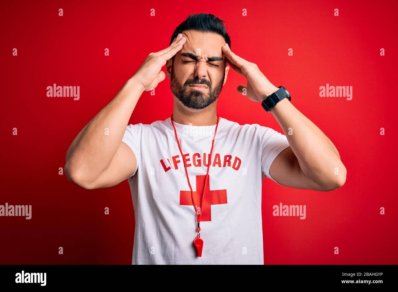 Young handsome lifeguard man with beard wearing whistle over isolated ...