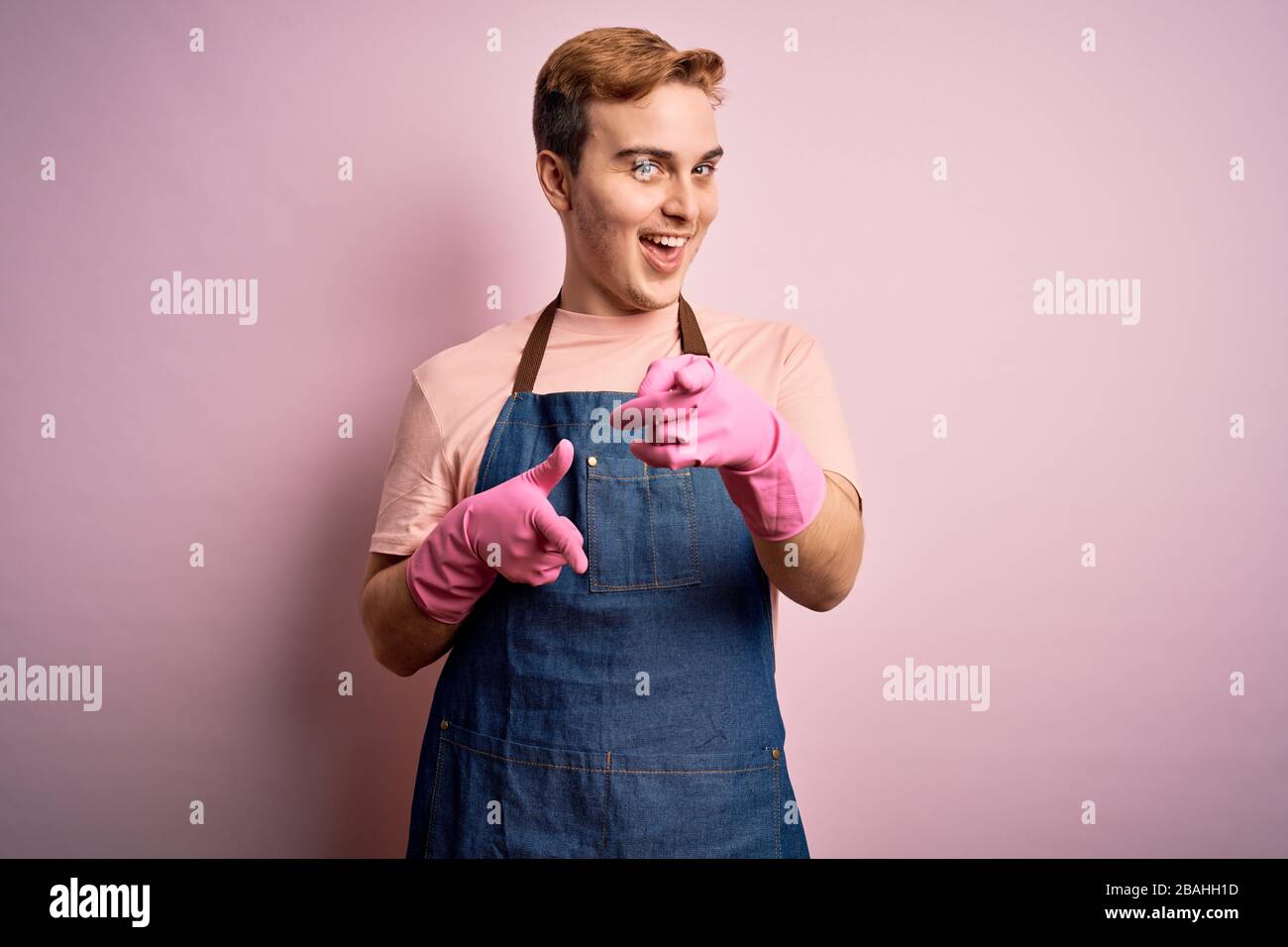 Young Handsome Redhead Cleaner Man Doing Housework Wearing Apron And Gloves Pointing Fingers To