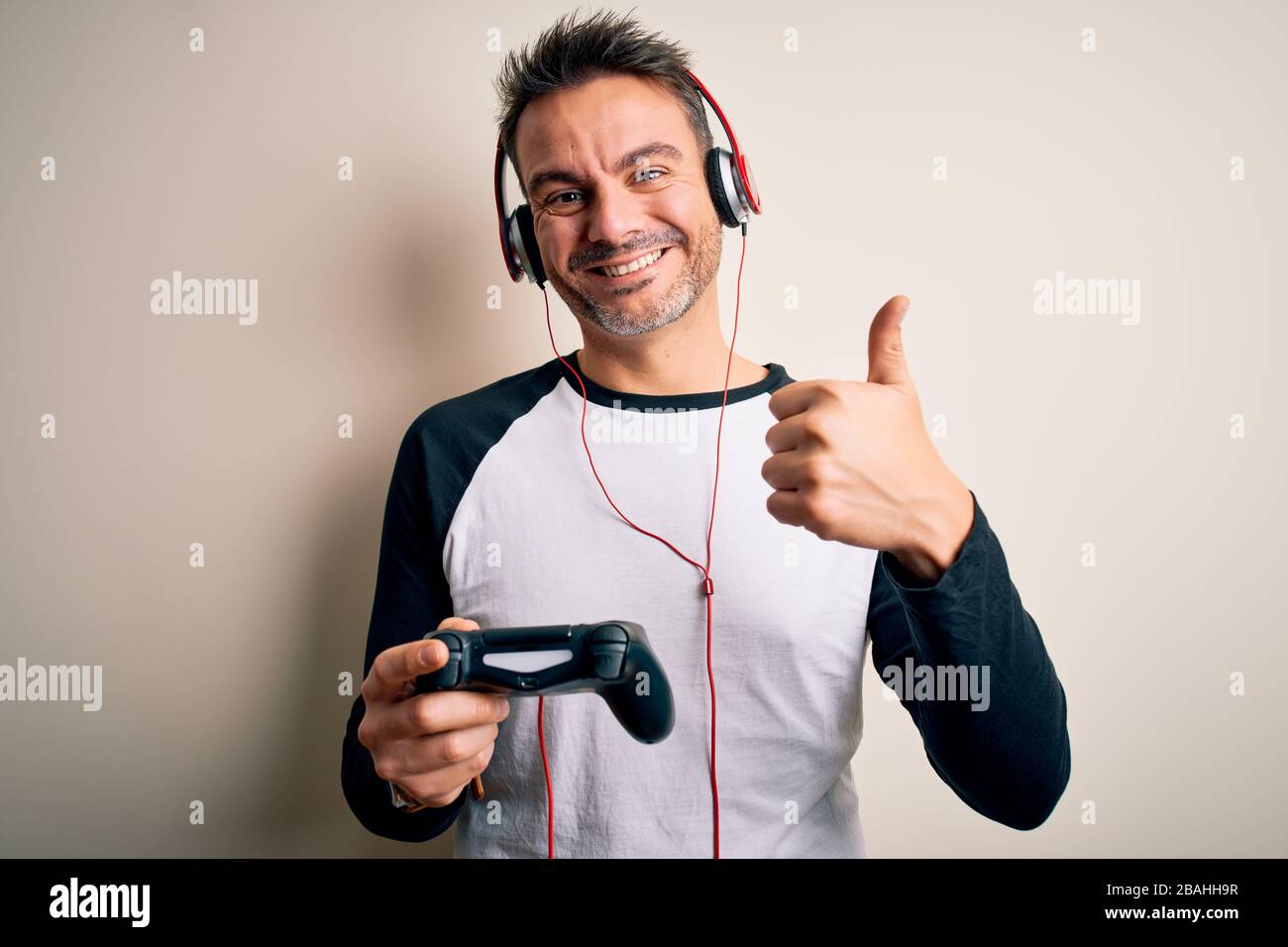 Young handsome gamer man playing video game using joystick and ...
