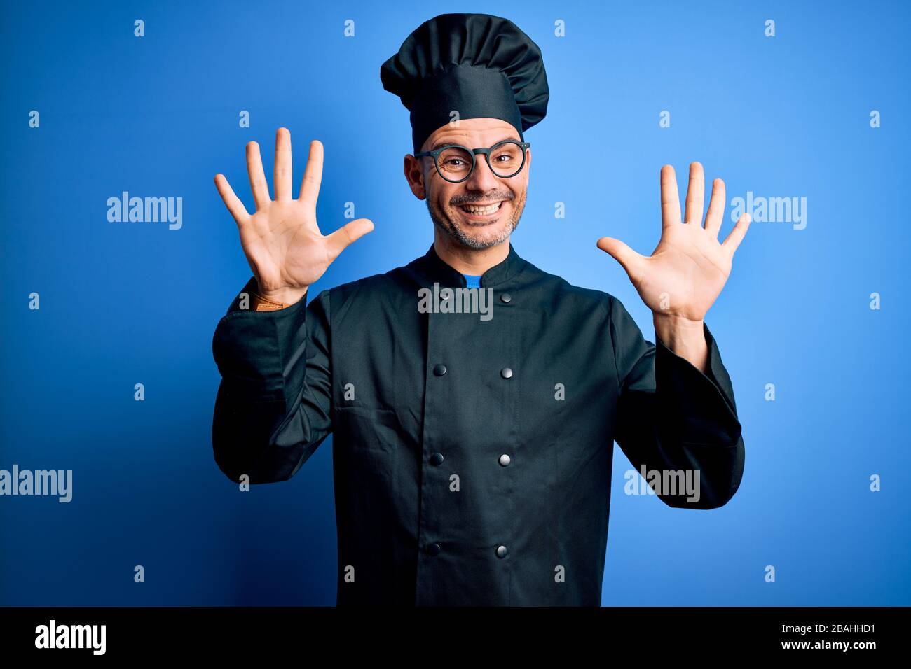 Young handsome chef man wearing cooker uniform and hat over isolated ...