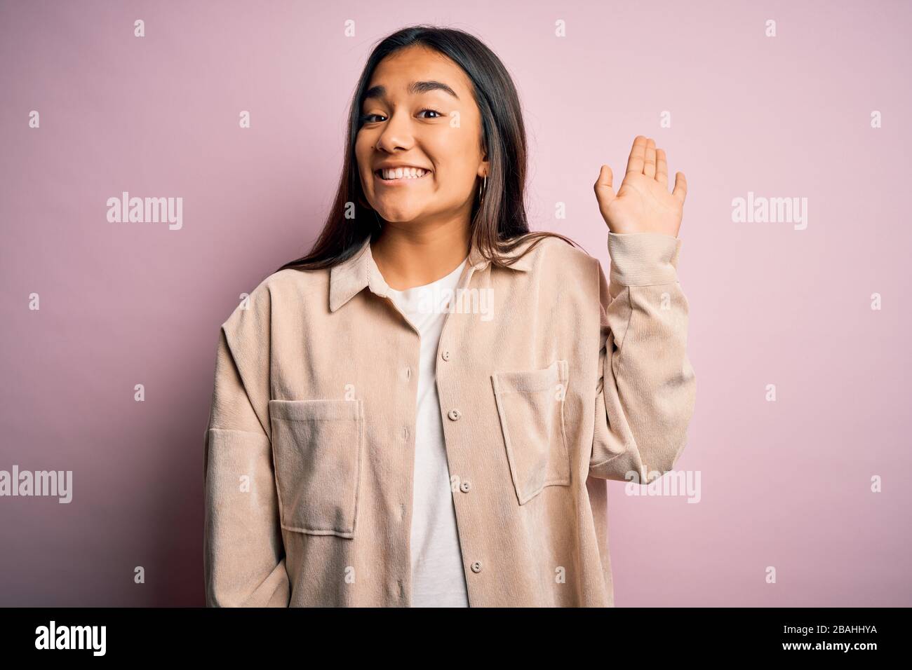 Young beautiful asian woman wearing casual shirt standing over pink ...