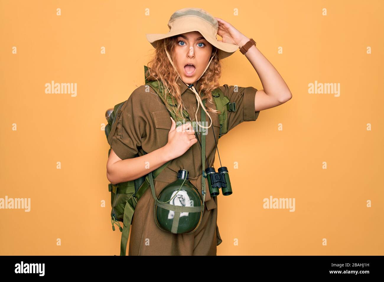 Young blonde explorer woman with blue eyes hiking wearing backpack and ...