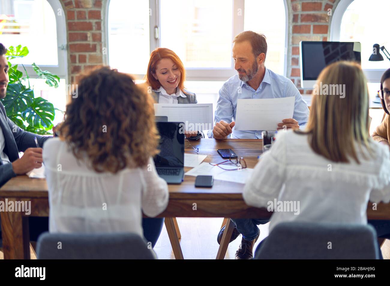 Group of business workers working together. Sitting on desk using ...