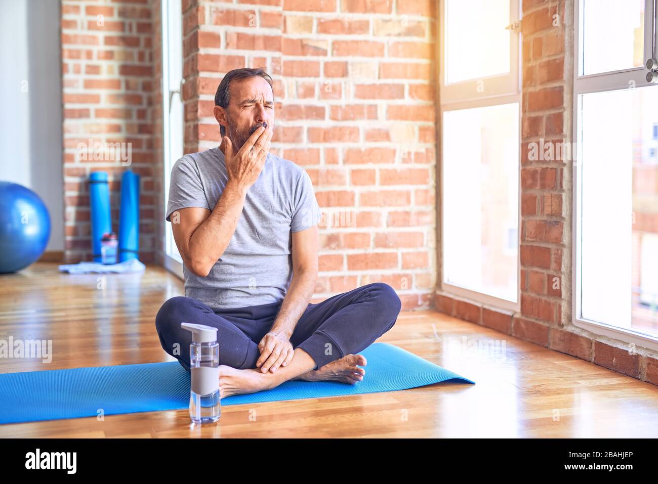 Middle age handsome sportman sitting on mat doing stretching yoga ...