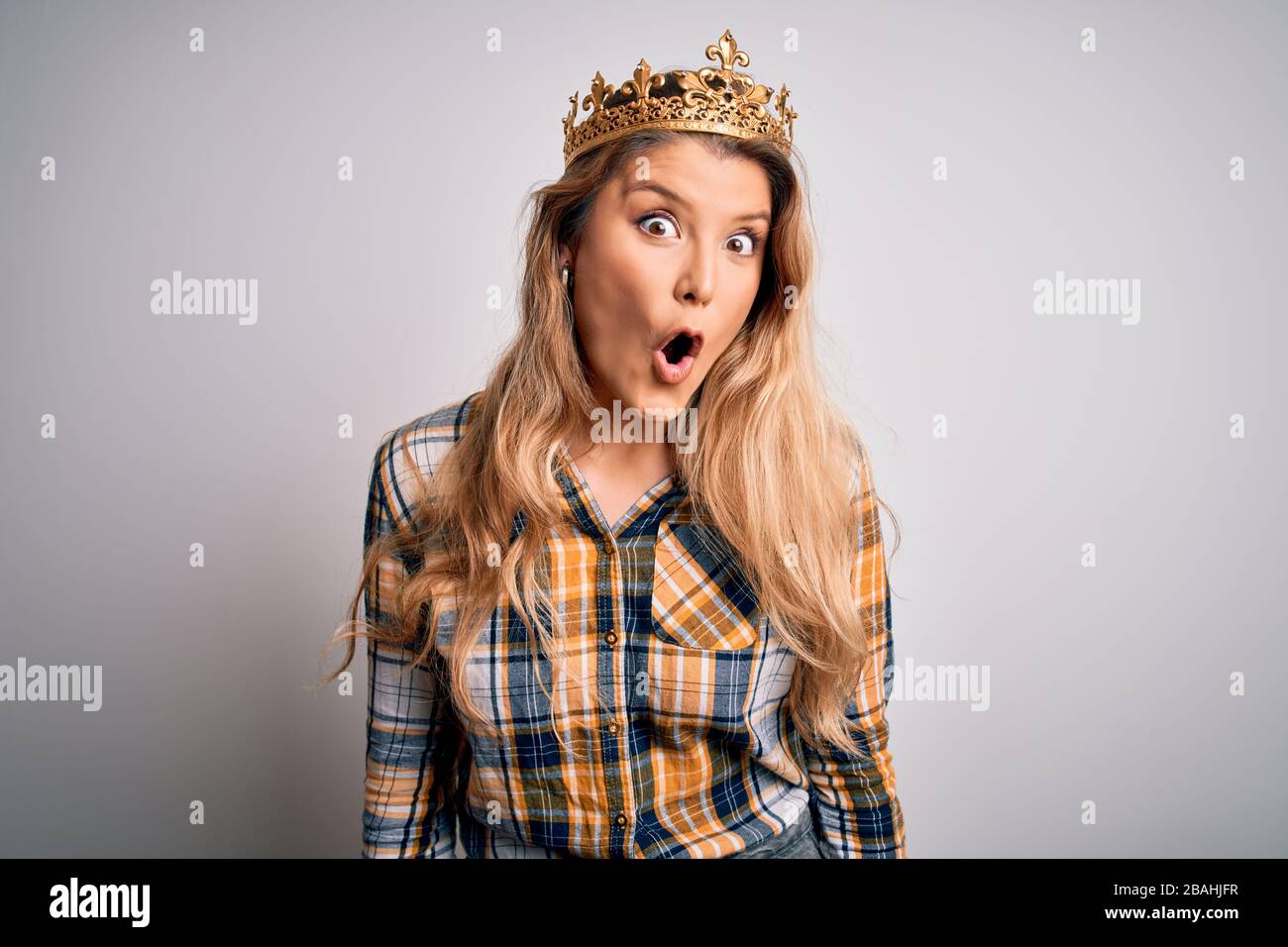 Young beautiful blonde woman wearing golden crown of queen over ...