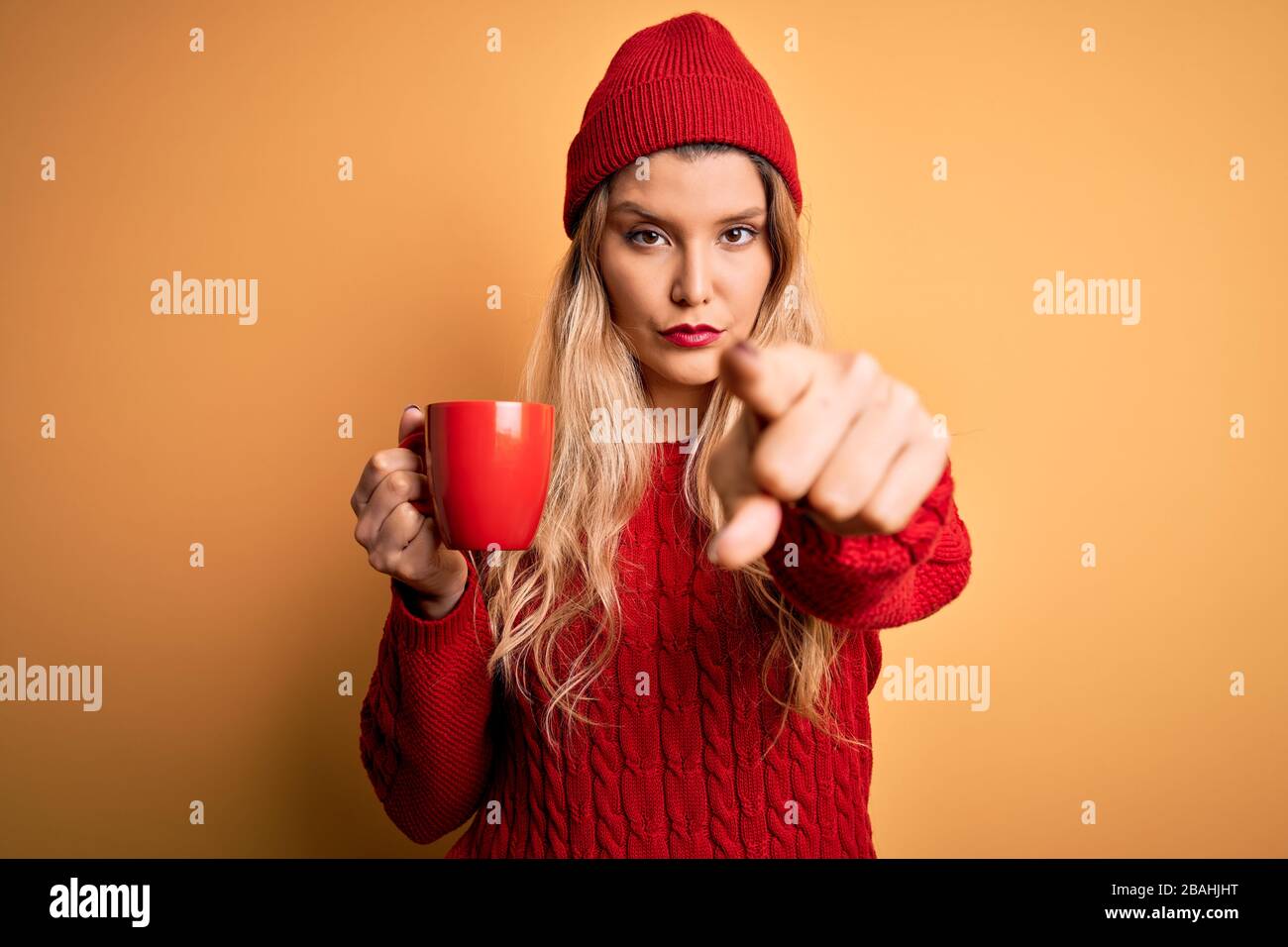 Young beautiful blonde woman drinking red mug of coffee over isolated ...