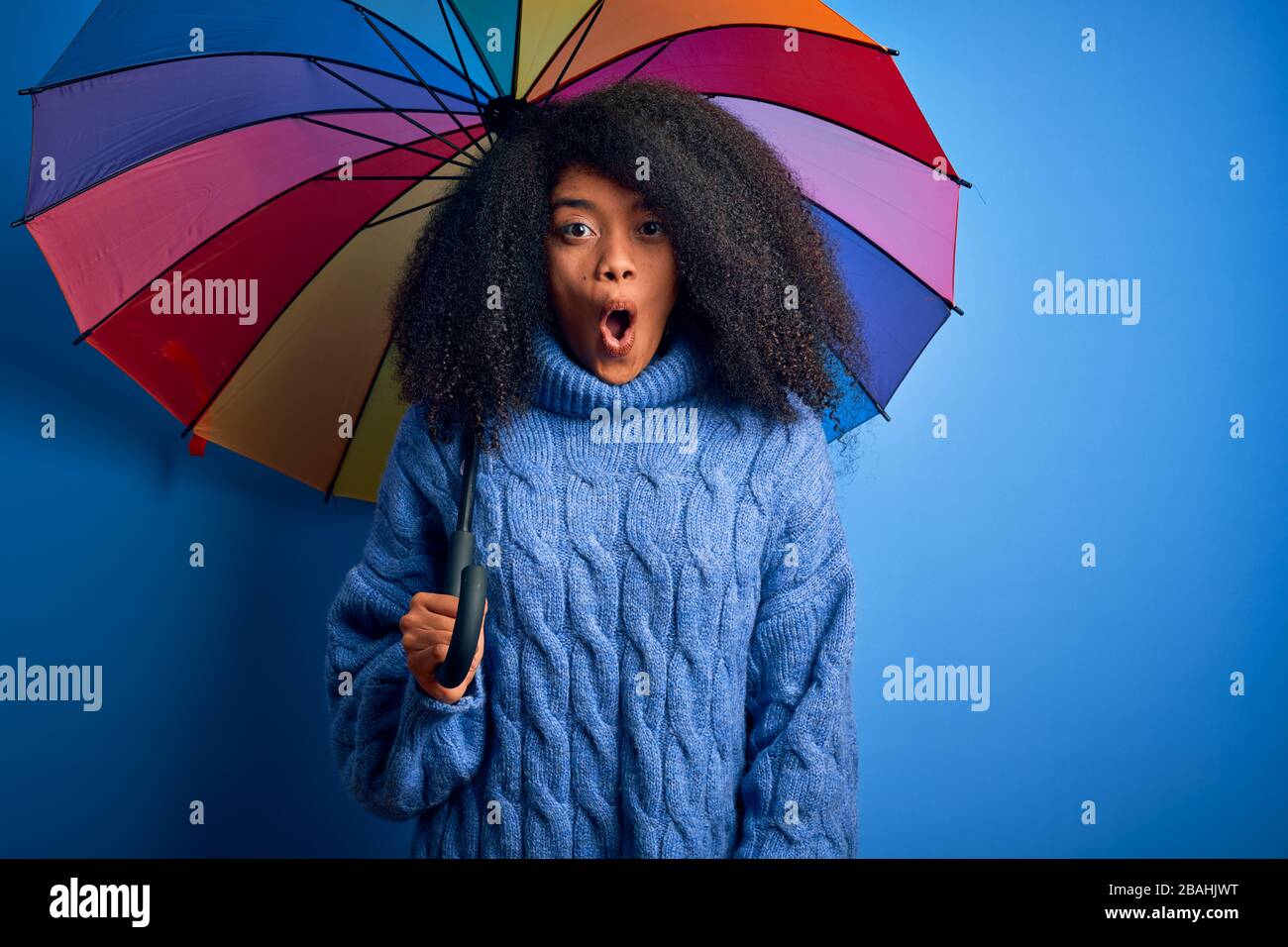 Young african american woman with afro hair under colorful umbrella for ...