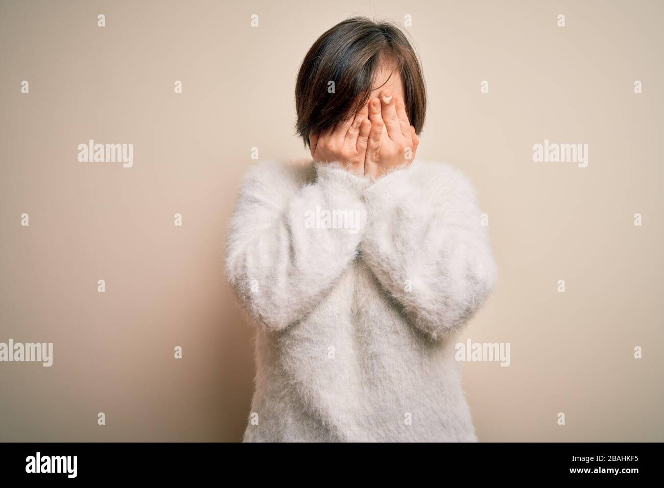 Young down syndrome woman standing over isolated background with sad ...