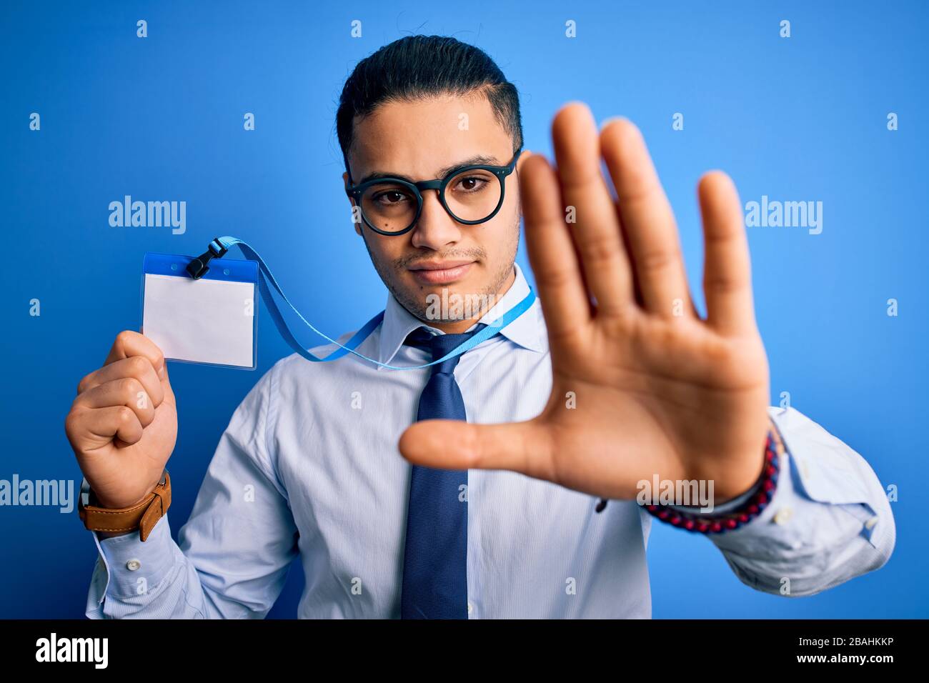 Young brazilian call center agent man holding id identification card ...