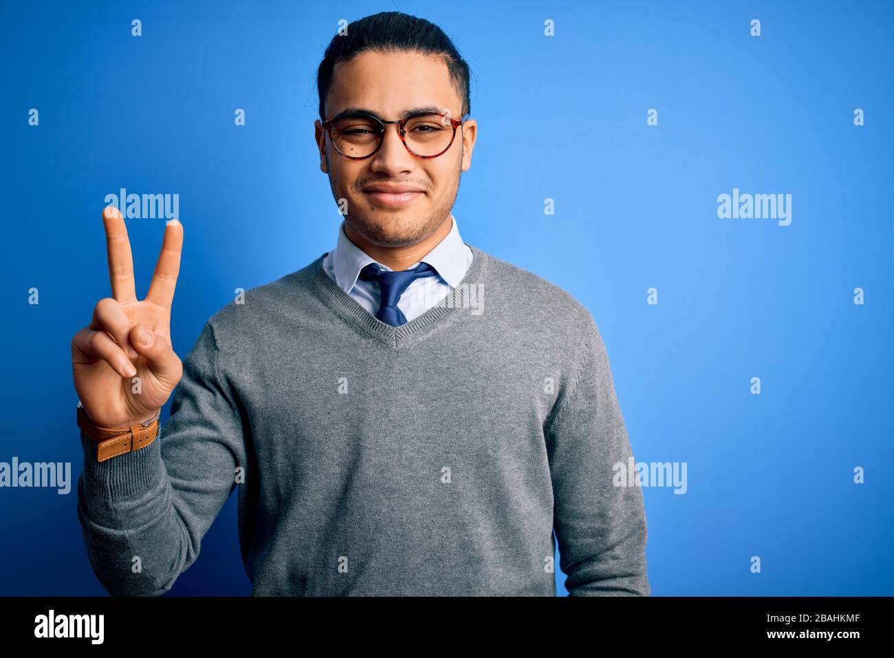 Young brazilian businessman wearing tie standing over isolated blue ...