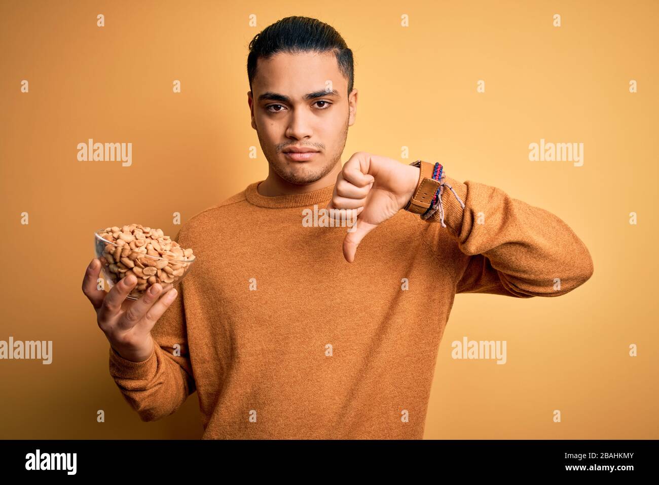 Young brazilian man holding bowl with healthy salty peanuts over ...