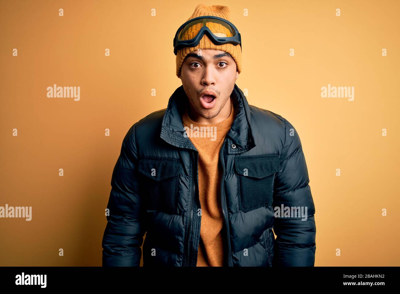 Young brazilian skier man wearing snow sportswear and ski goggles over ...