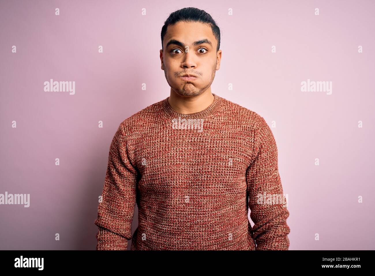 Young brazilian man wearing casual sweater standing over isolated pink ...