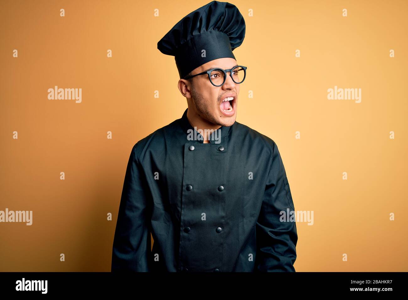 Young brazilian chef man wearing cooker uniform and hat over isolated ...