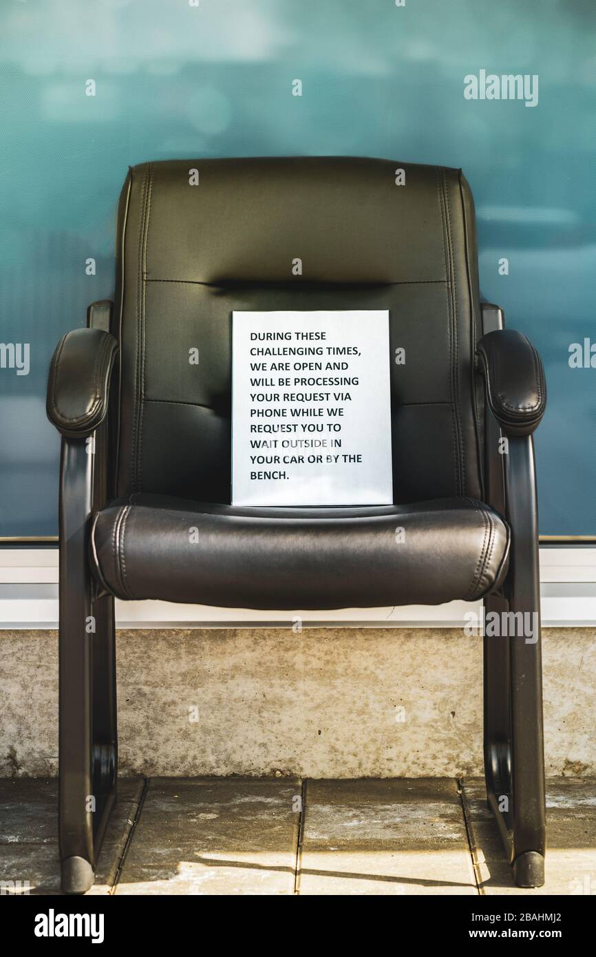 Social and physical distance signs on black office chair outside ...