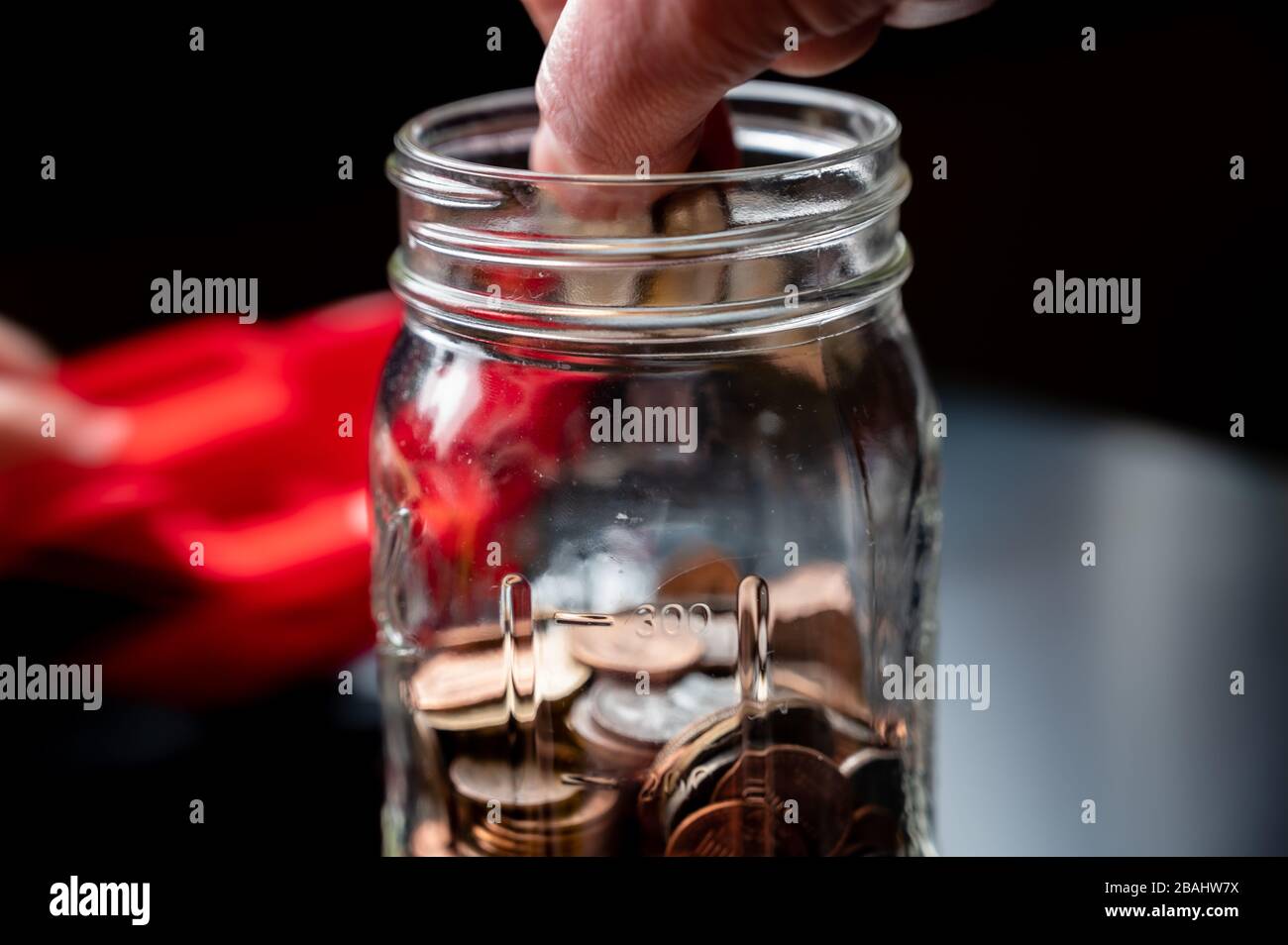 Two fingers holding coins to be dropped into a glass jar Stock Photo ...