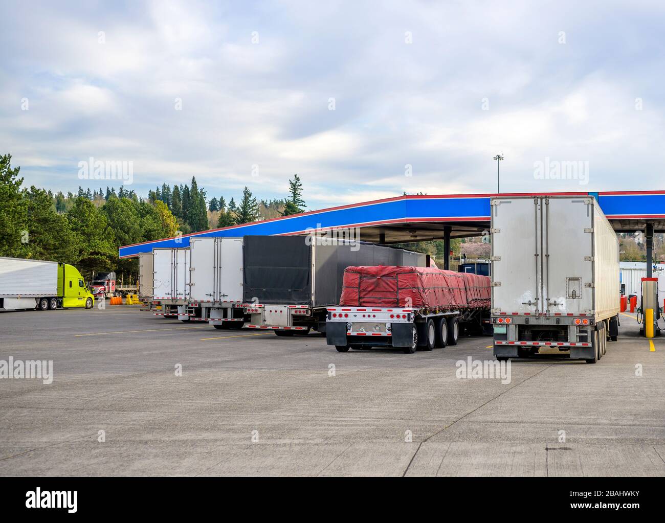 Different makes and models of big rigs semi trucks with loaded semi ...