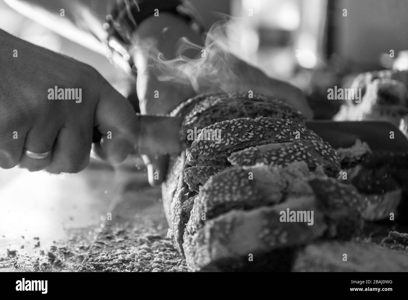 Isolated close up of a baker cutting a fresh steaming loaf of bread ...