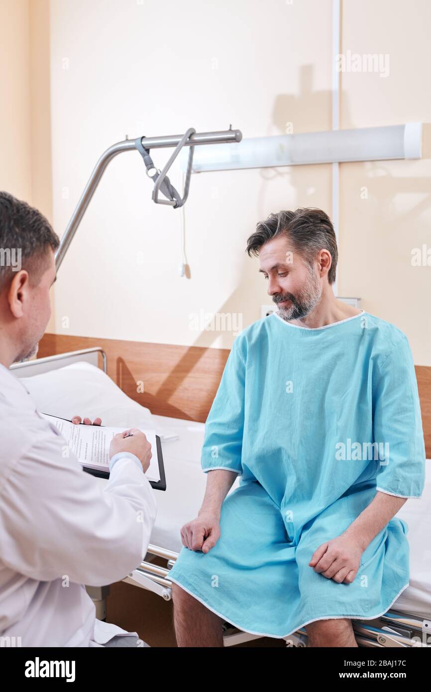Over shoulder view of doctor pointing at place for signature while ...