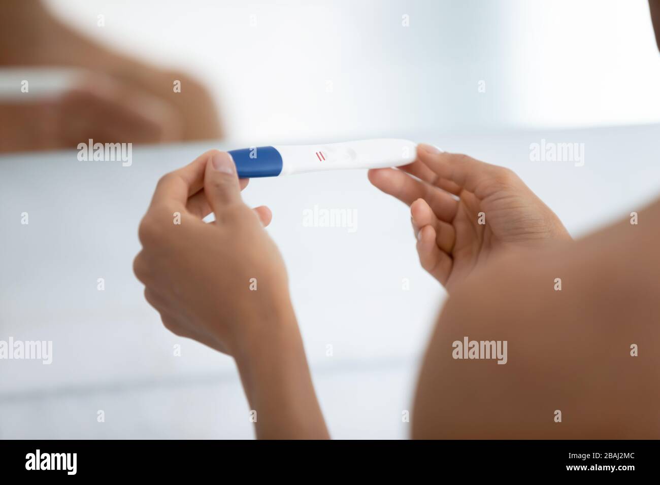 Closeup view over shoulder of woman holding positive pregnancy test ...