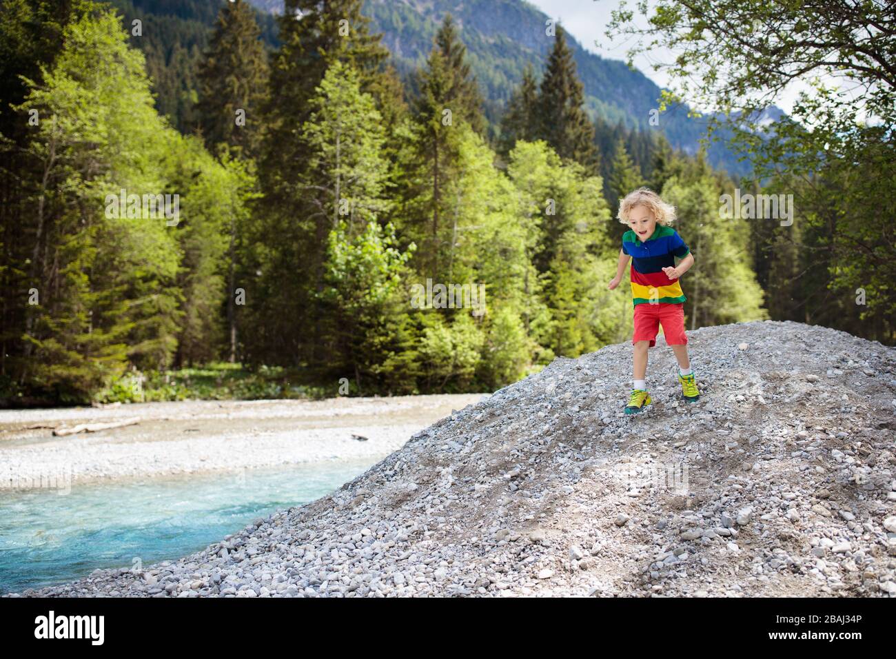 Children hiking in the Alps mountains crossing river. Kids play in ...