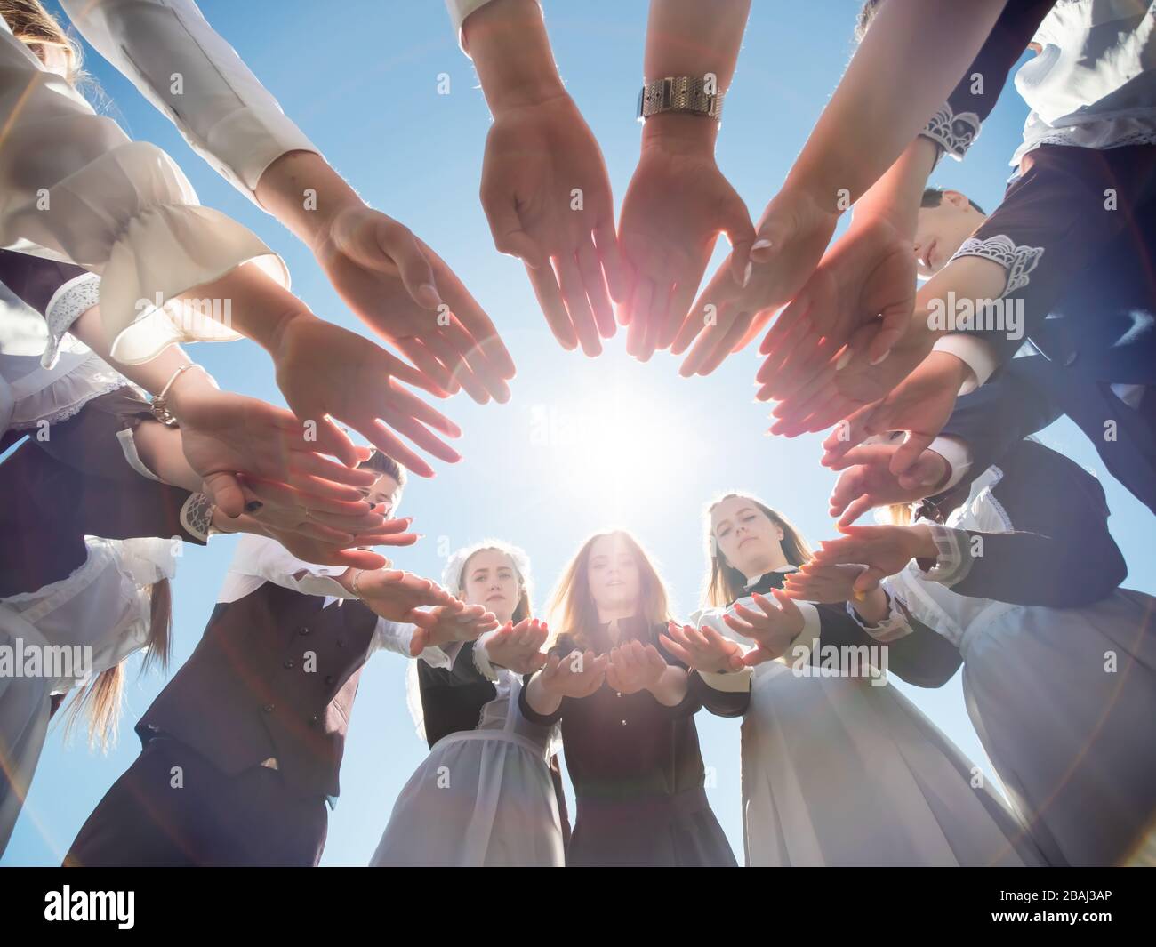 Students graduates make the shape of a circle from the palms of their ...