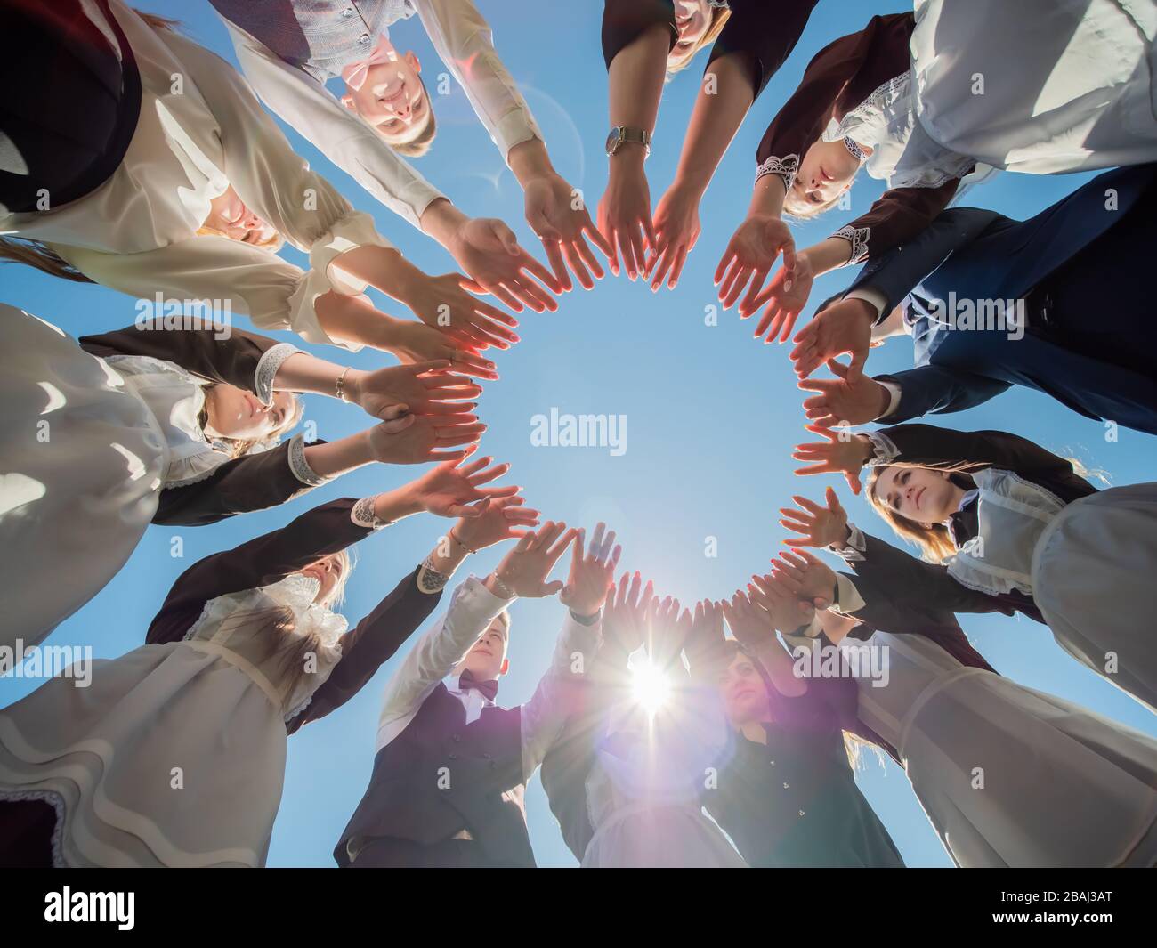 Students graduates make the shape of a circle from the palms of their ...