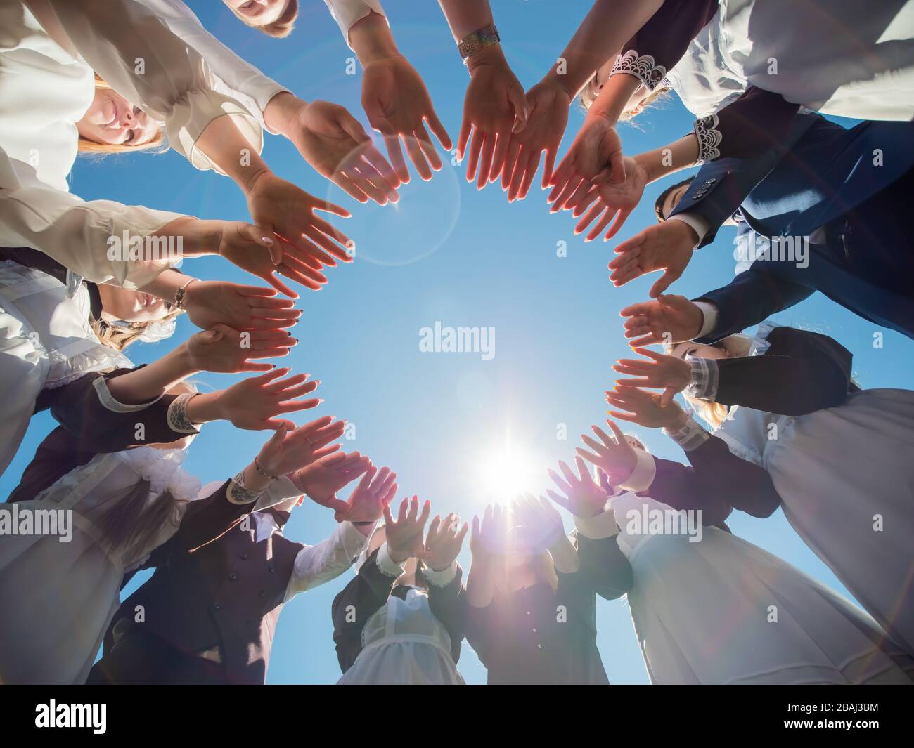 Students graduates make the shape of a circle from the palms of their ...