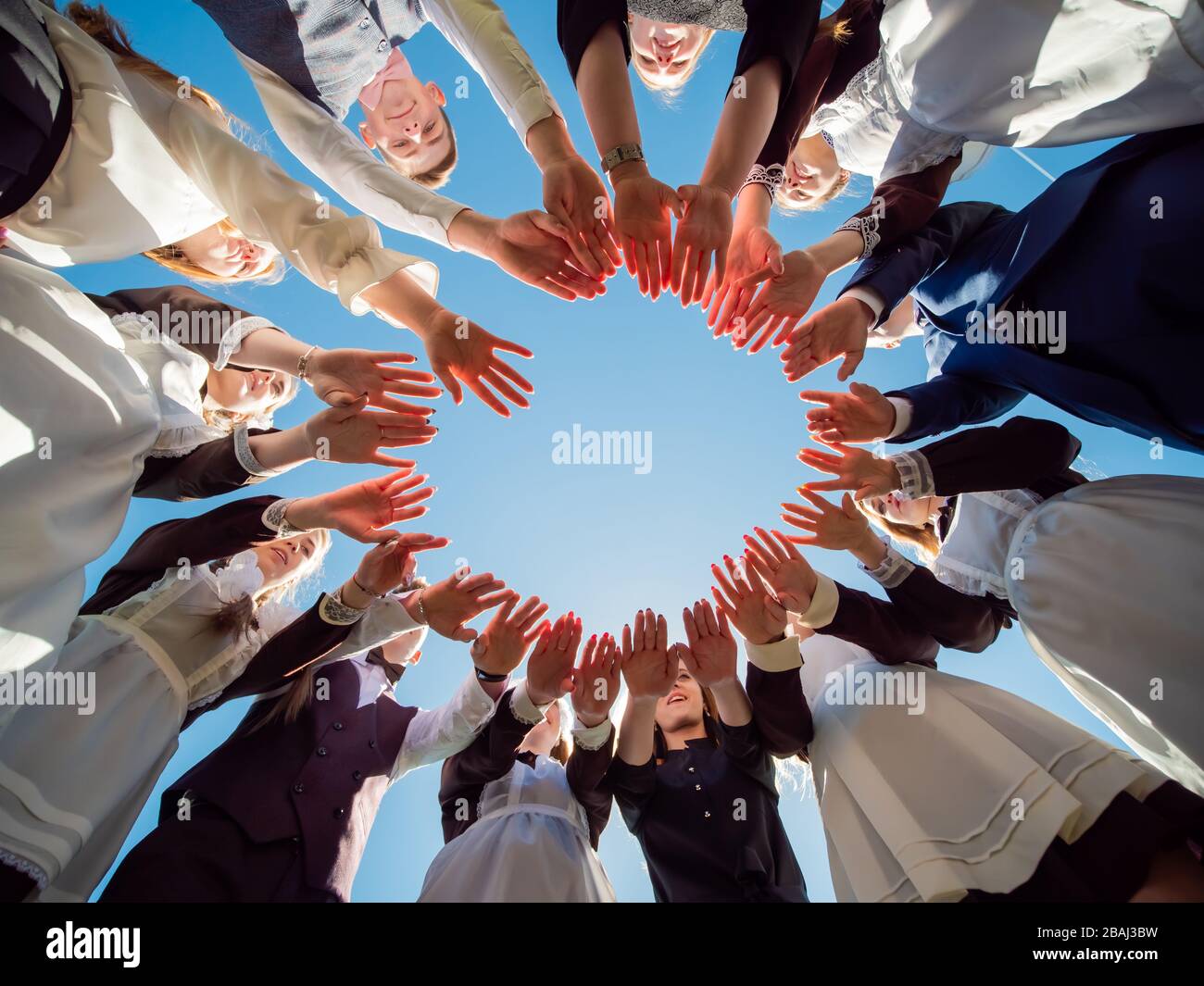 Students graduates make the shape of a circle from the palms of their ...