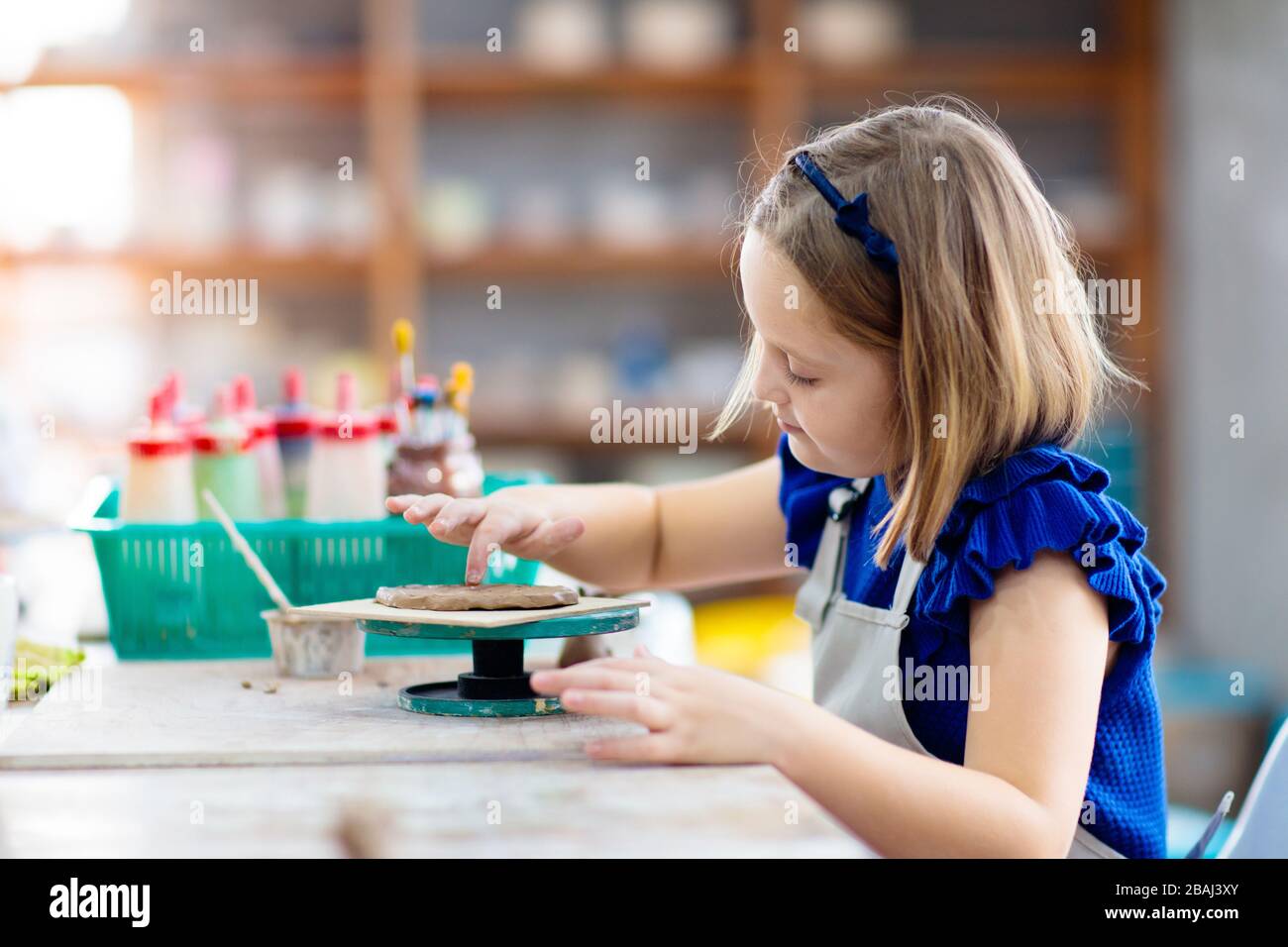 Child working on pottery wheel. Kids arts and crafts class in workshop ...