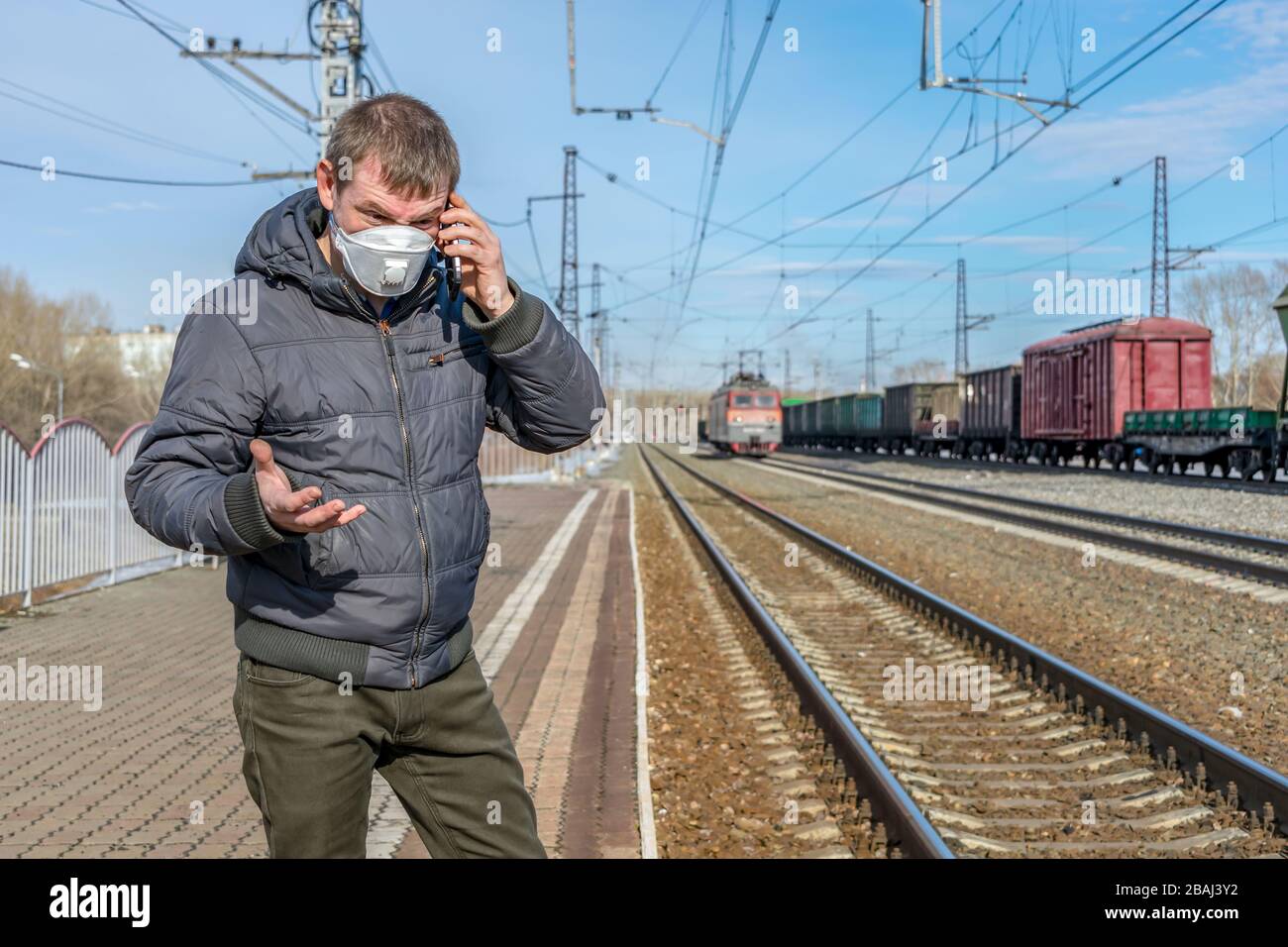 A very angry man is standing at the train station and talking on the ...