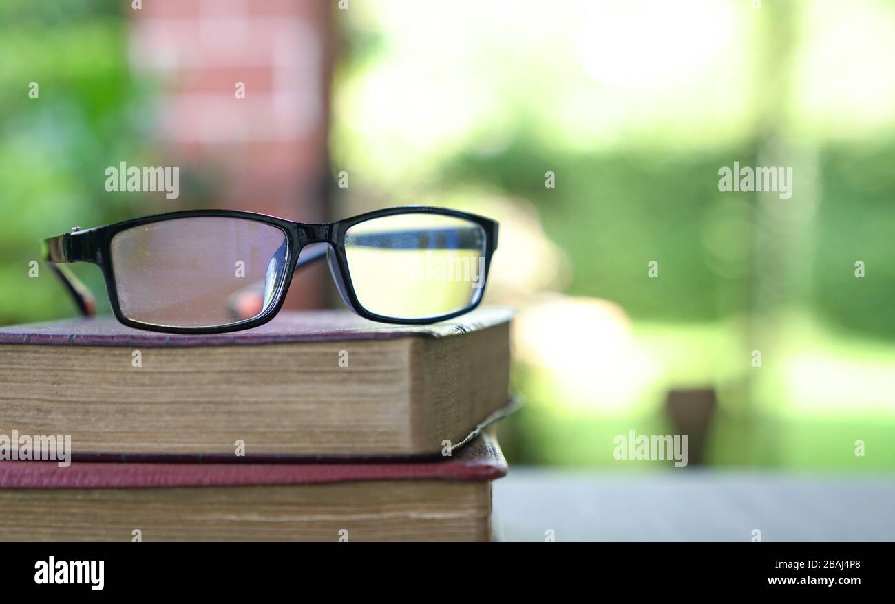 Stack of books with reading glasses on top. Green nature background ...