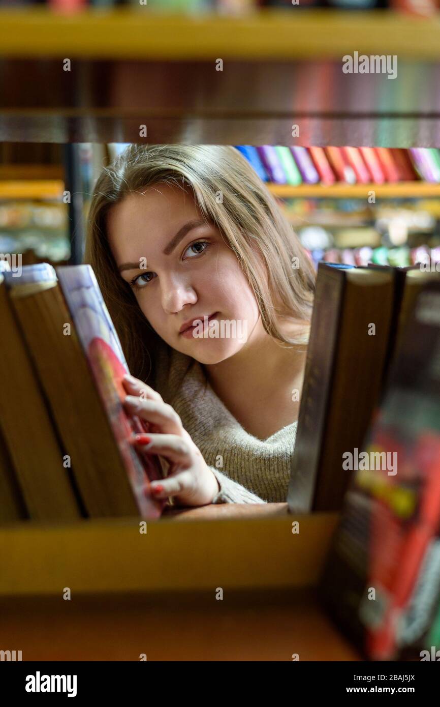 Young girl looking for book on bookshelf in library Stock Photo - Alamy