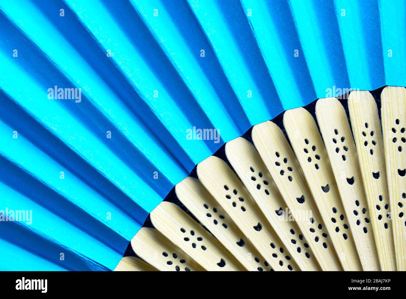 Detail of open blue folding hand fan. A fan provides cooling air during ...