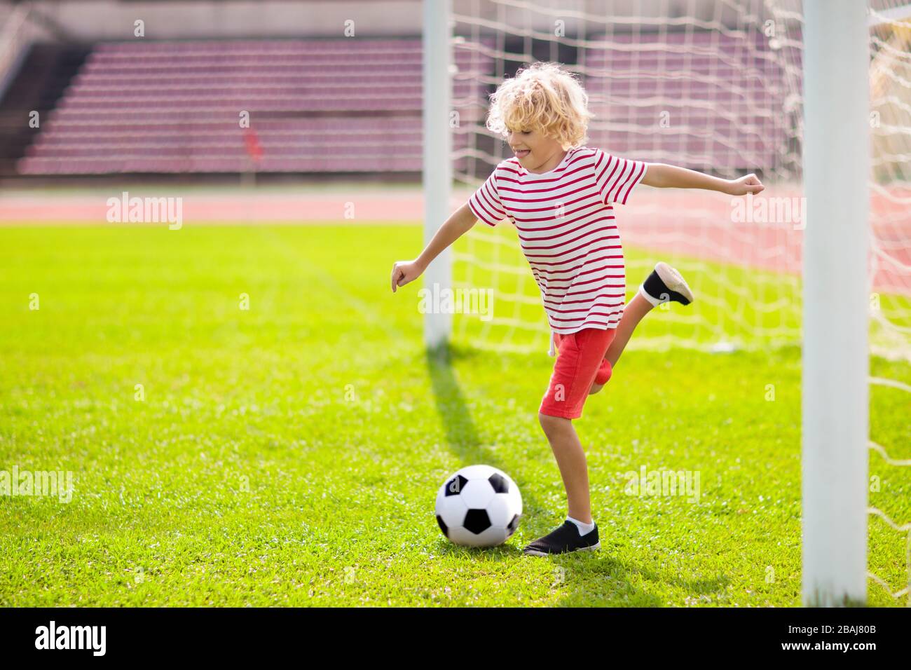 Kids play football on outdoor stadium field. Children score a goal ...