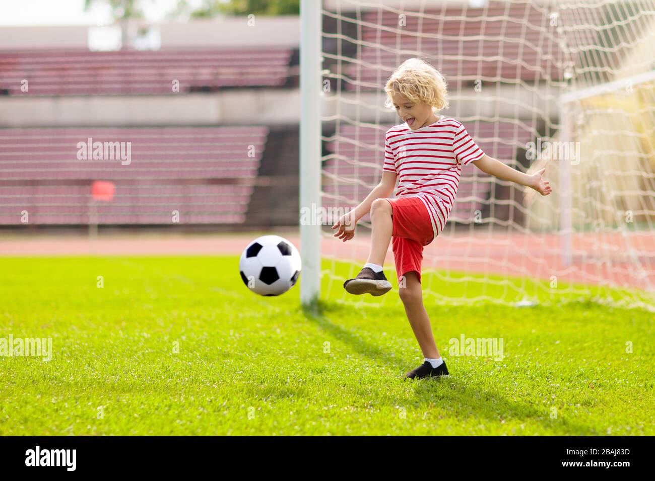 Kids play football on outdoor stadium field. Children score a goal ...