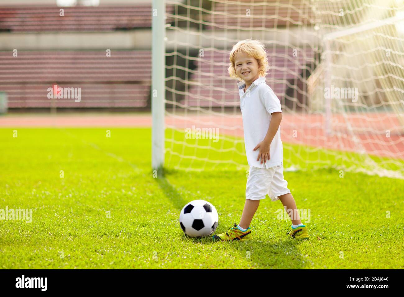 Kids play football on outdoor stadium field. Children score a goal ...