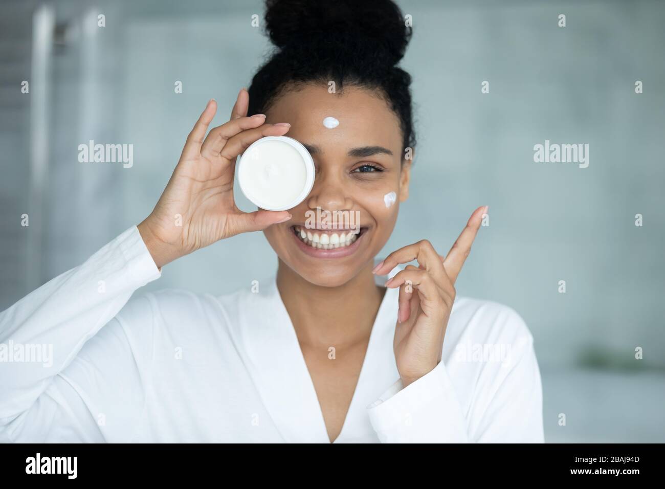 African woman applied cream on face holds jar feels happy Stock Photo ...