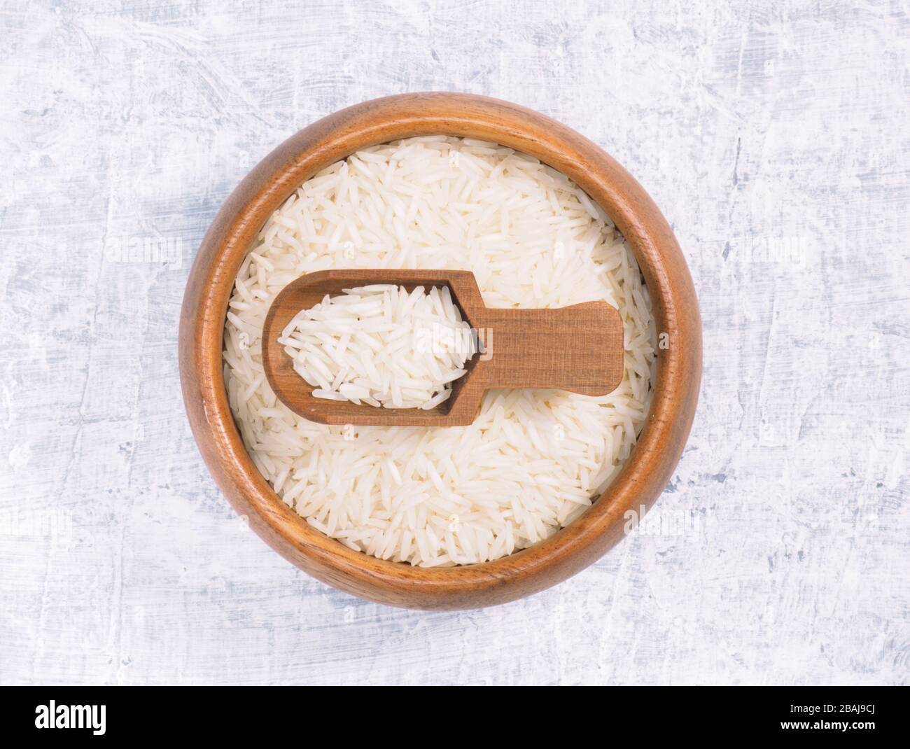Indian long grain Basmati rice in brown wooden bowl and scoop on white ...