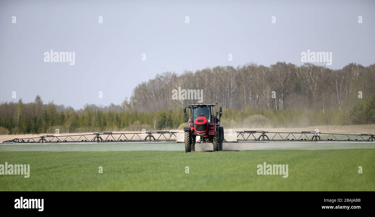 Tractor spraying wheat field with sprayer Stock Photo - Alamy