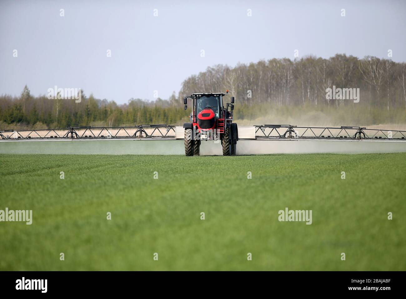 Tractor spraying wheat field with sprayer Stock Photo - Alamy