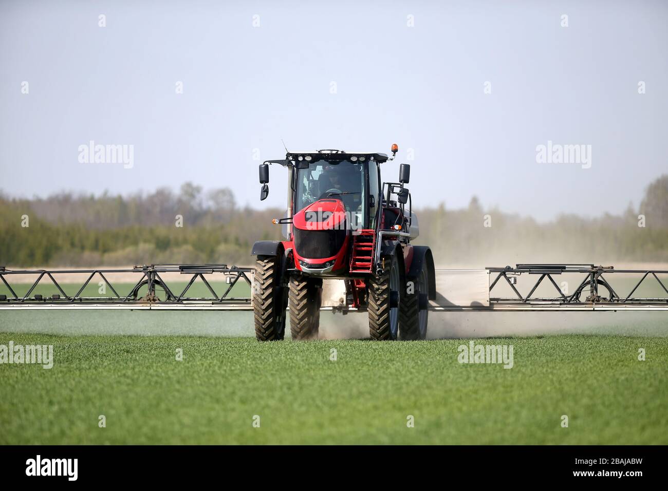 Tractor spraying wheat field with sprayer Stock Photo - Alamy
