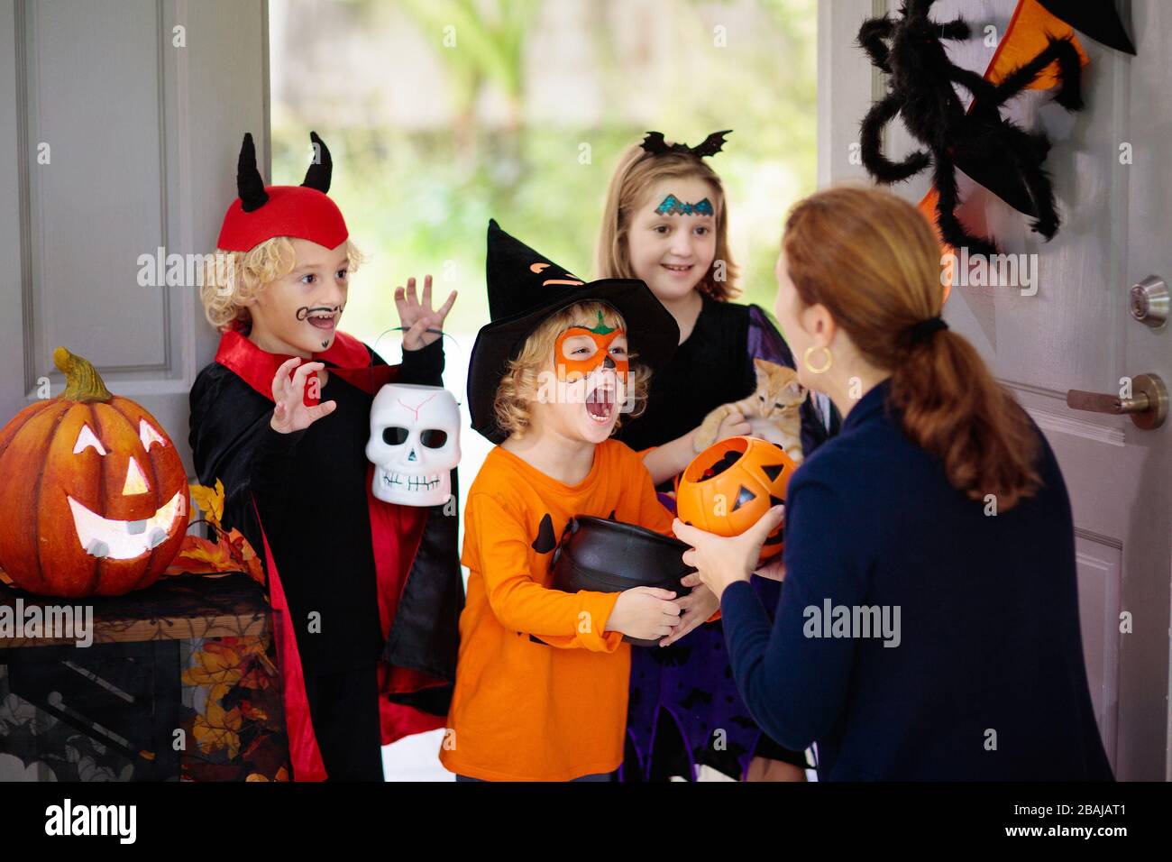 Kids trick or treat on Halloween night. Child and mother at decorated ...