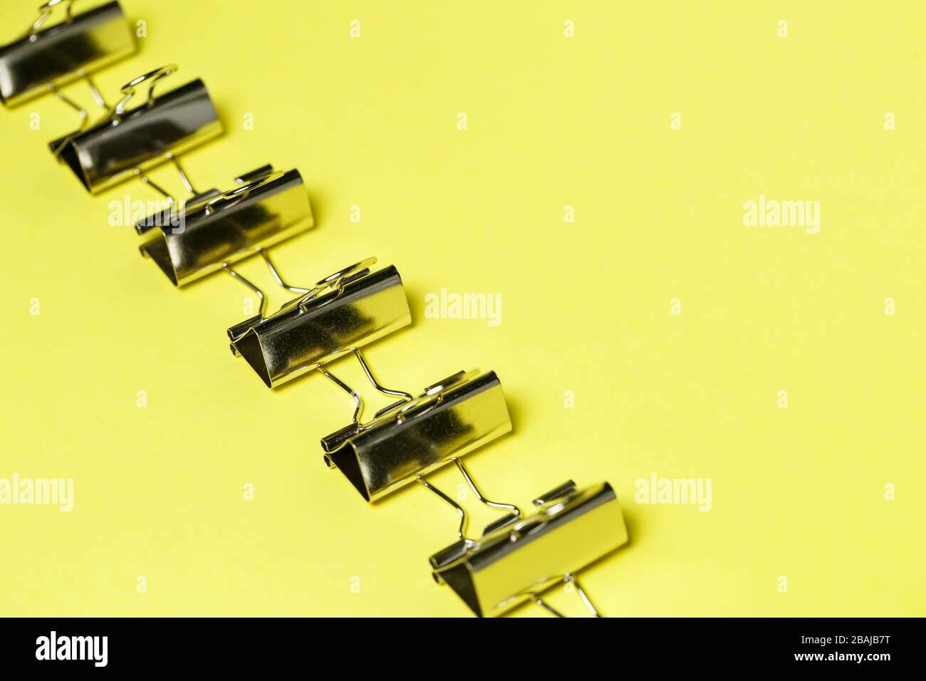 Metal binders on a yellow background. Stationery accessories. Paper ...