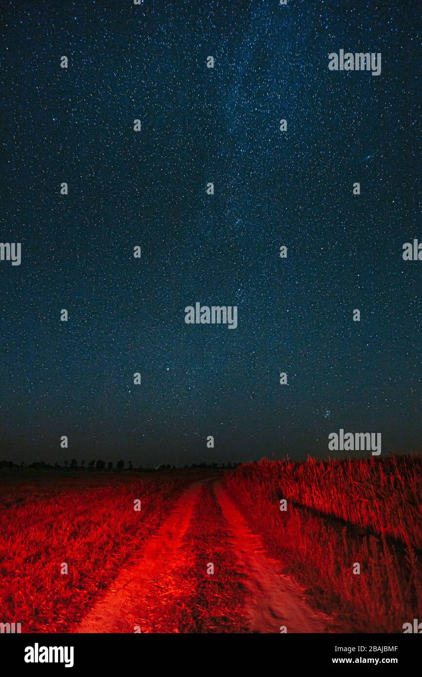 Night Starry Sky With Glowing Stars Above Country Road Is Lit In Red ...
