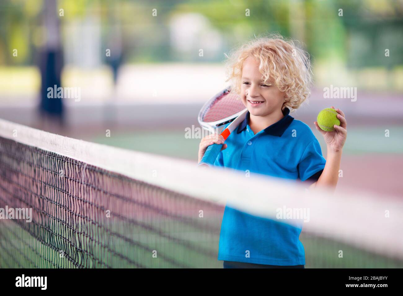 Child playing tennis on indoor court. Little boy with tennis racket and ...
