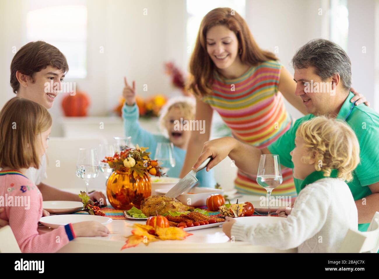 Family with kids eating Thanksgiving dinner. Roasted turkey and pumpkin ...