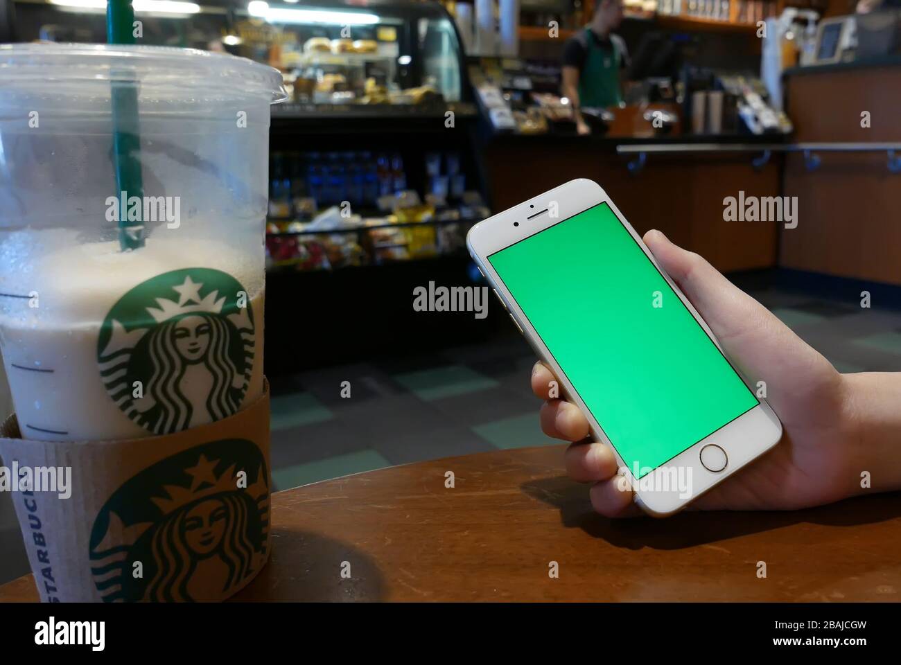 Hand holding green screen iphone inside Starbucks store Stock Photo - Alamy