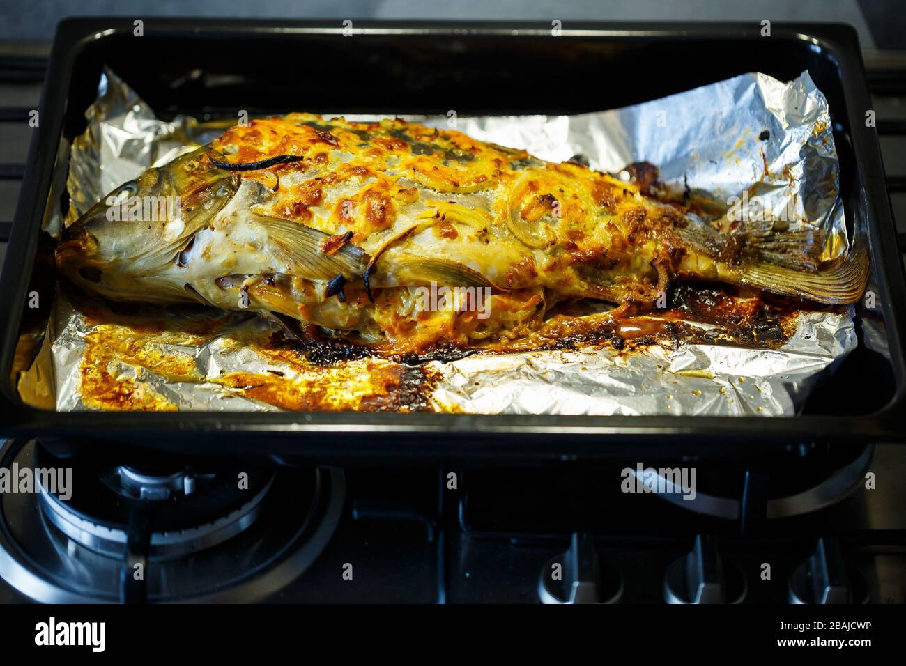 Baked fish with onions and cheese Stock Photo - Alamy